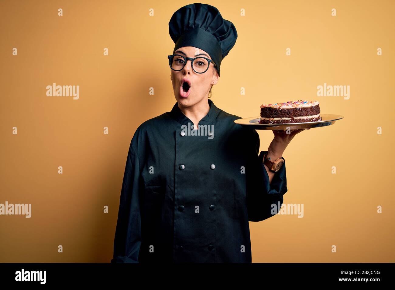 Young beautiful brunette baker woman wearing cooker uniform and hat ...