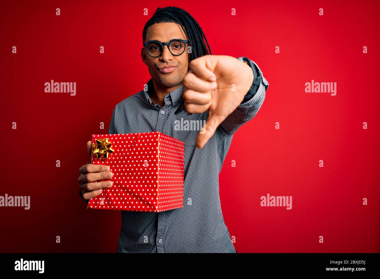 African American man with dreadlocks holding present box over red ...