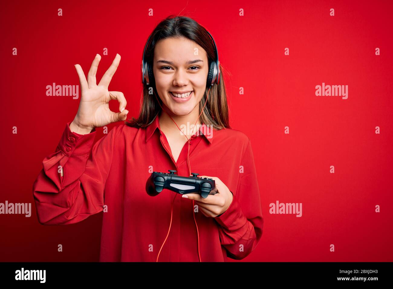 Young beautiful brunette gamer girl playing video game using joystick ...