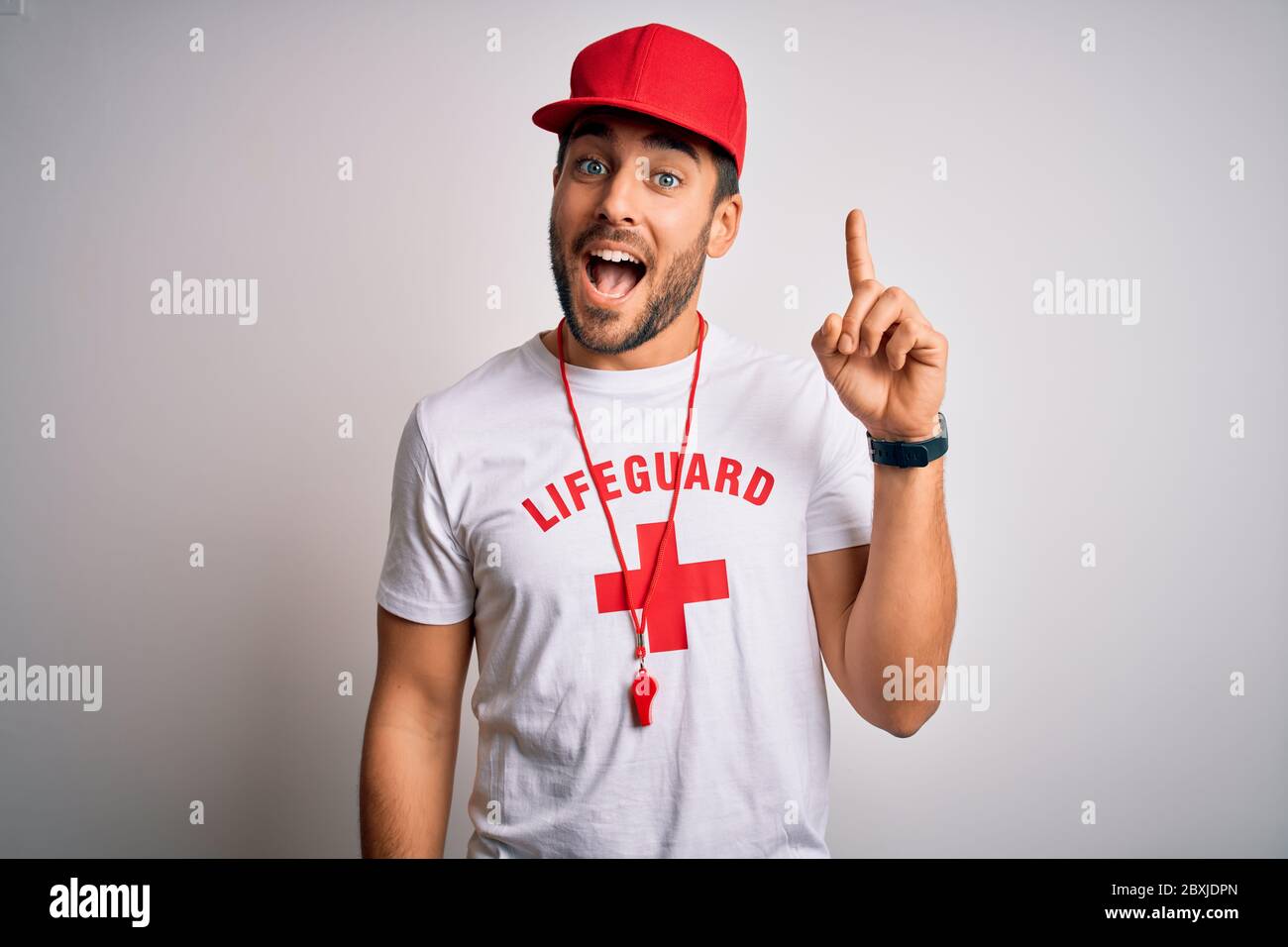 Young handsome lifeguard man with beard wearing t-shirt with red cross ...