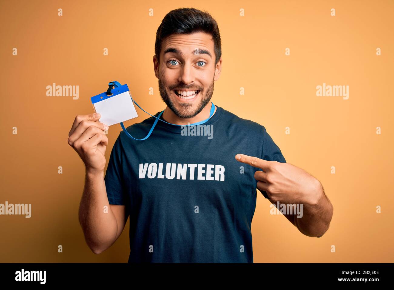 Handsome volunteer man with beard holding id card identification over ...