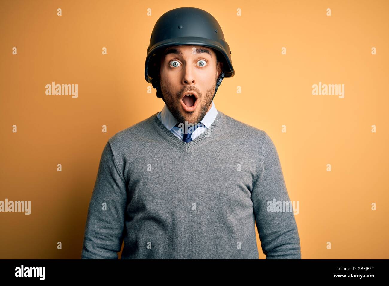 Young handsome businessman wearing military helmet over isolated yellow ...