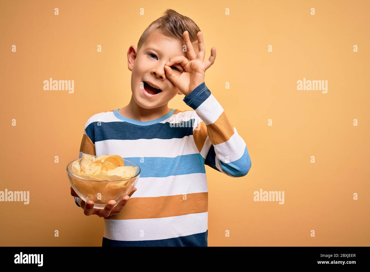 Young little caucasian kid eating unheatlhy potatoes crisps chips over ...
