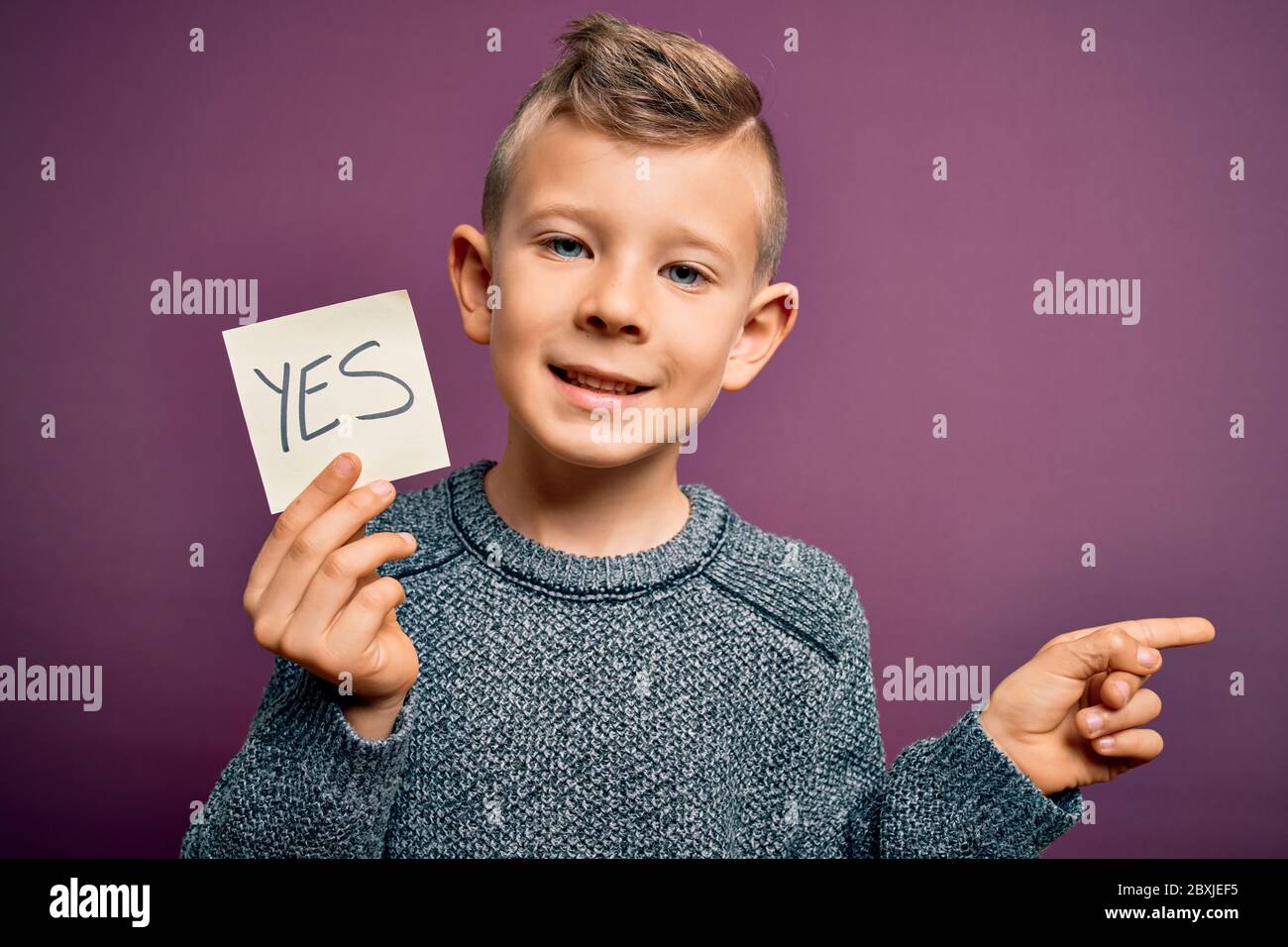 Young little caucasian kid showing YES word on a paper note as positive ...