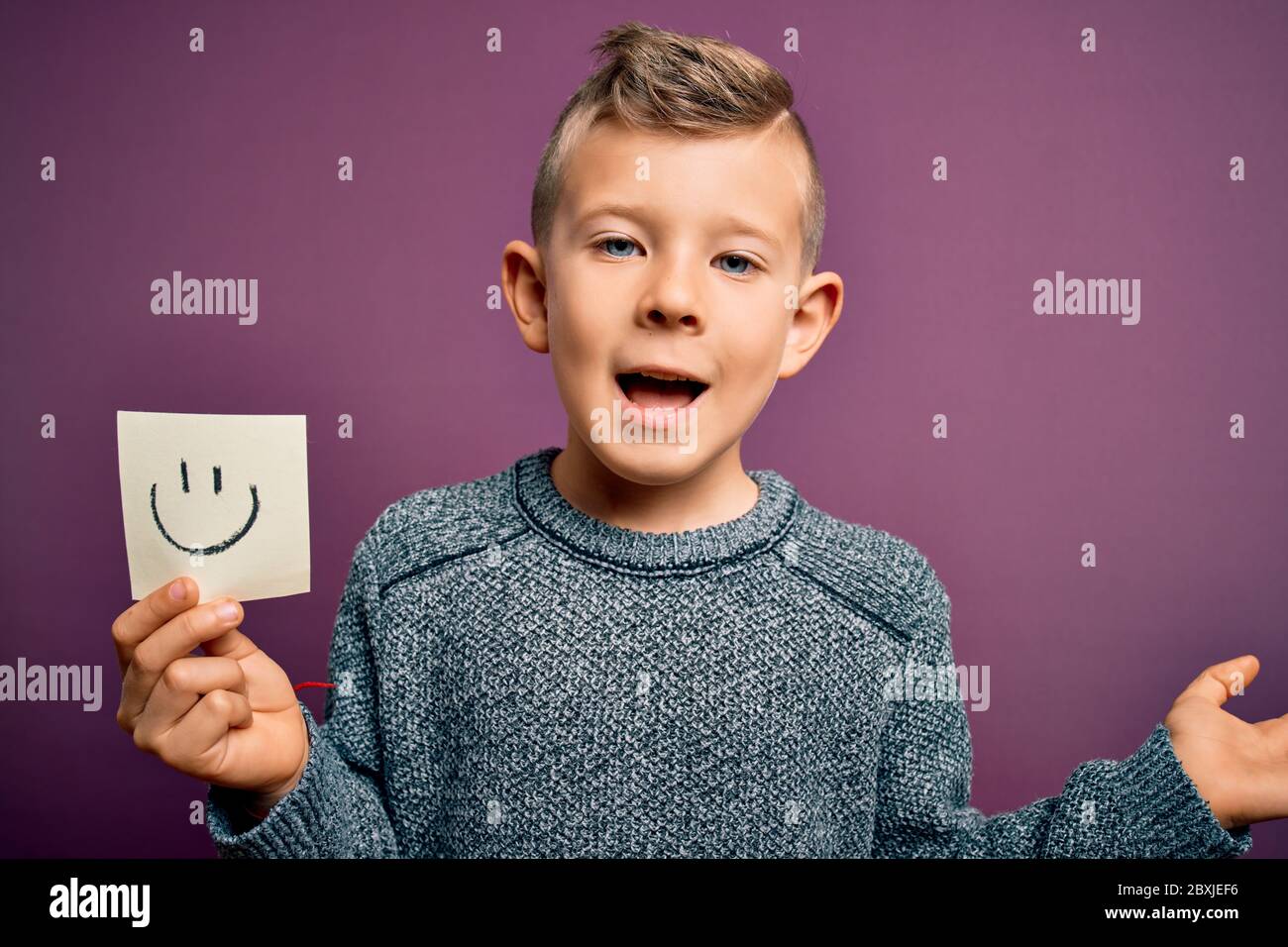 Young little caucasian kid showing smiley face on a paper note as happy ...