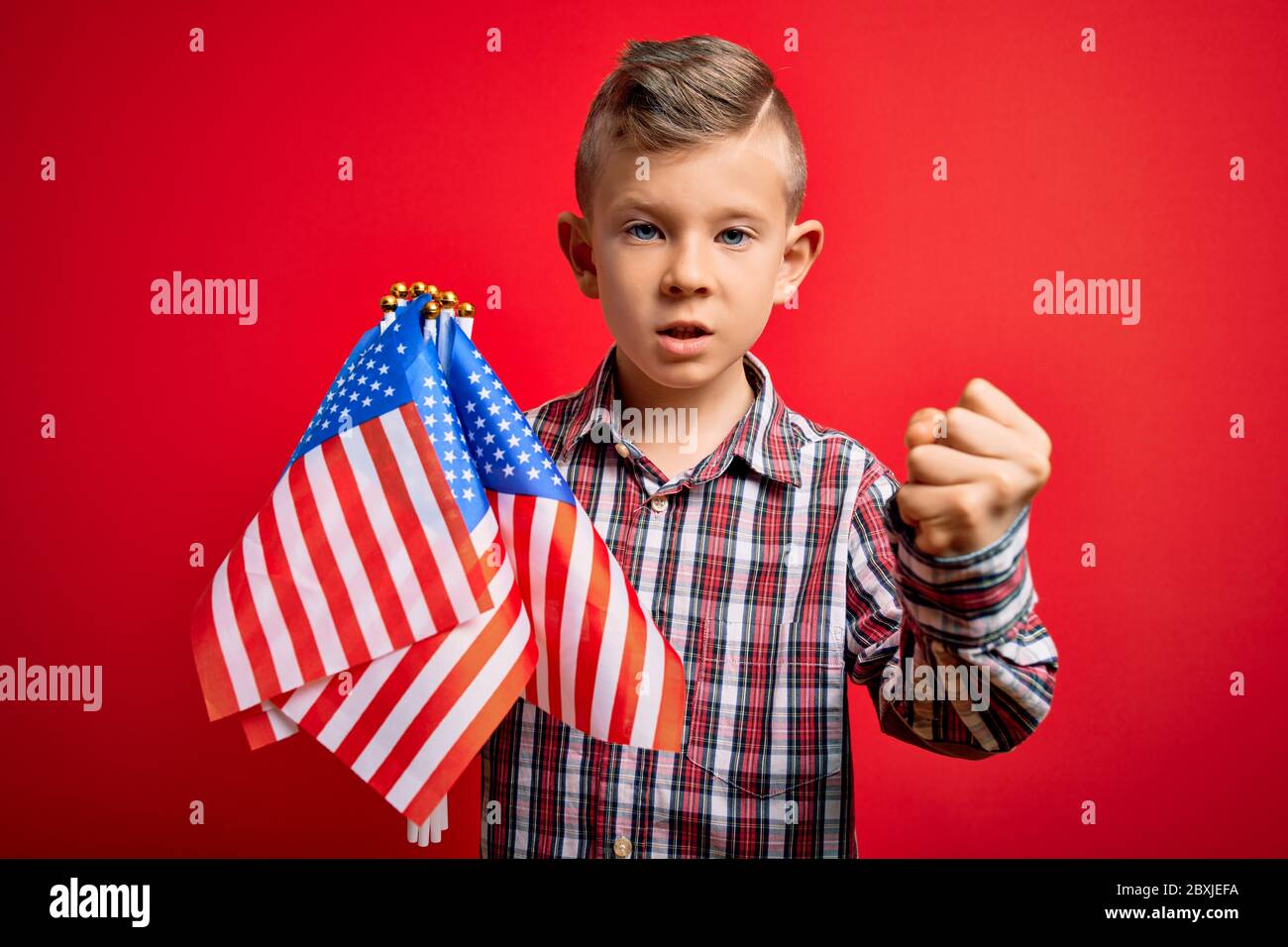 Young little american patriotic caucasian kid holding flag of USA over ...