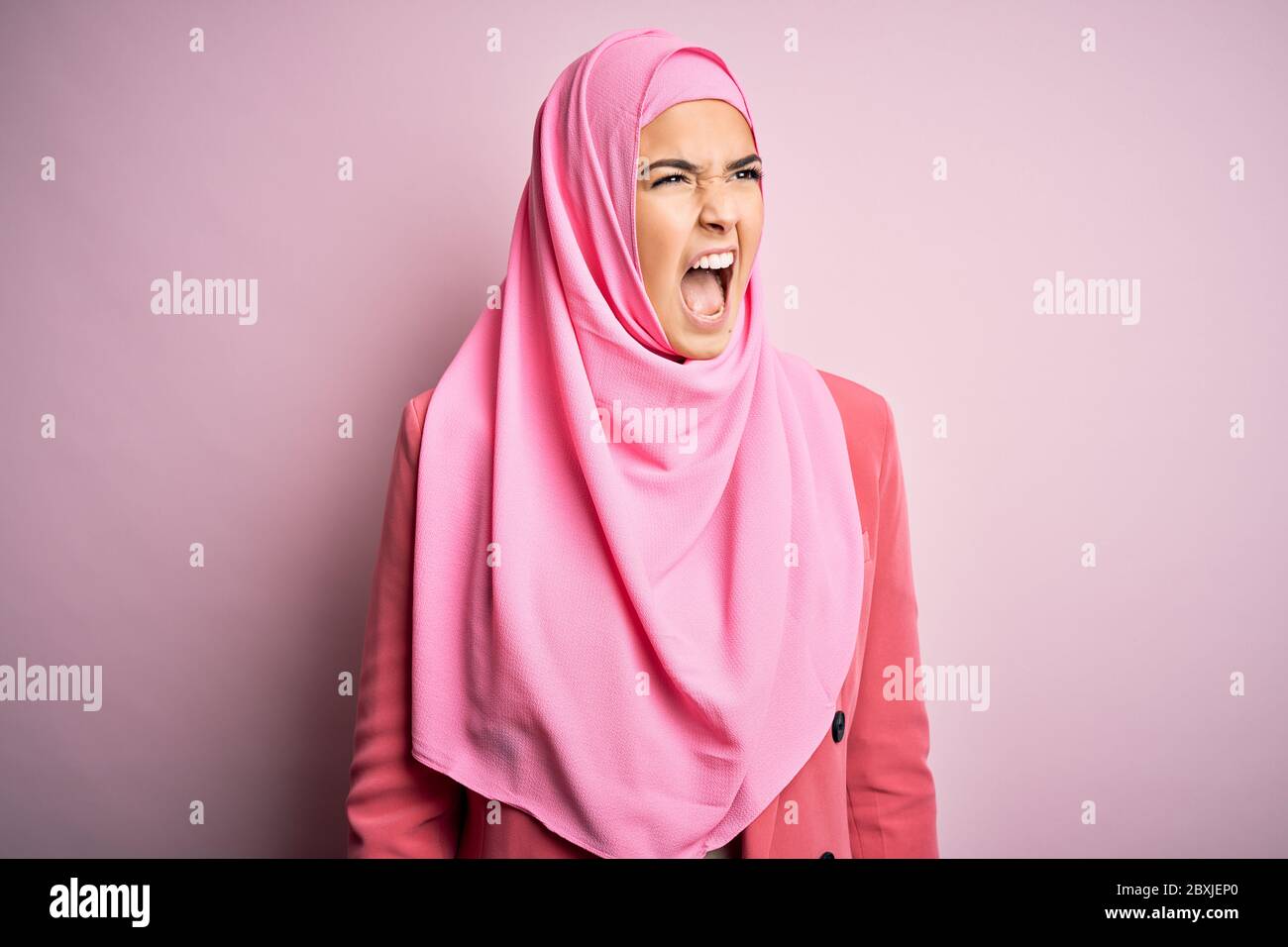Young beautiful girl wearing muslim hijab standing over isolated pink ...