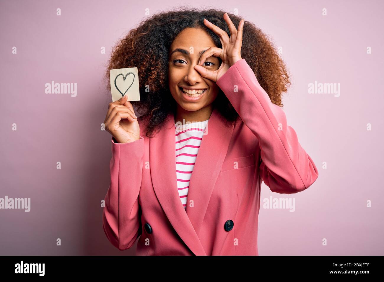 Young african american woman with afro hair holding paper with heart ...