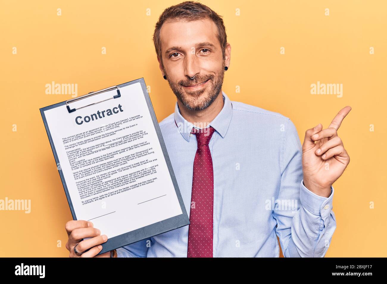 Young handsome man holding clipboard with contract document smiling ...