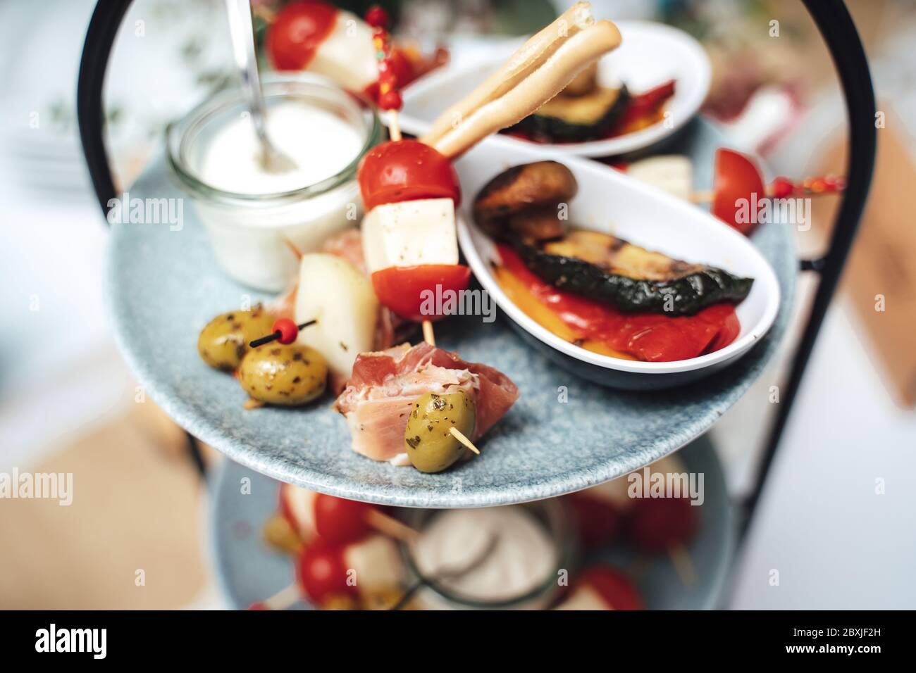 Multi-tiered plate stand with small snacks and ingredients. Stuffed ...