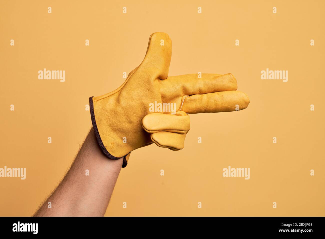 Hand of caucasian young man with gardener glove over isolated yellow ...