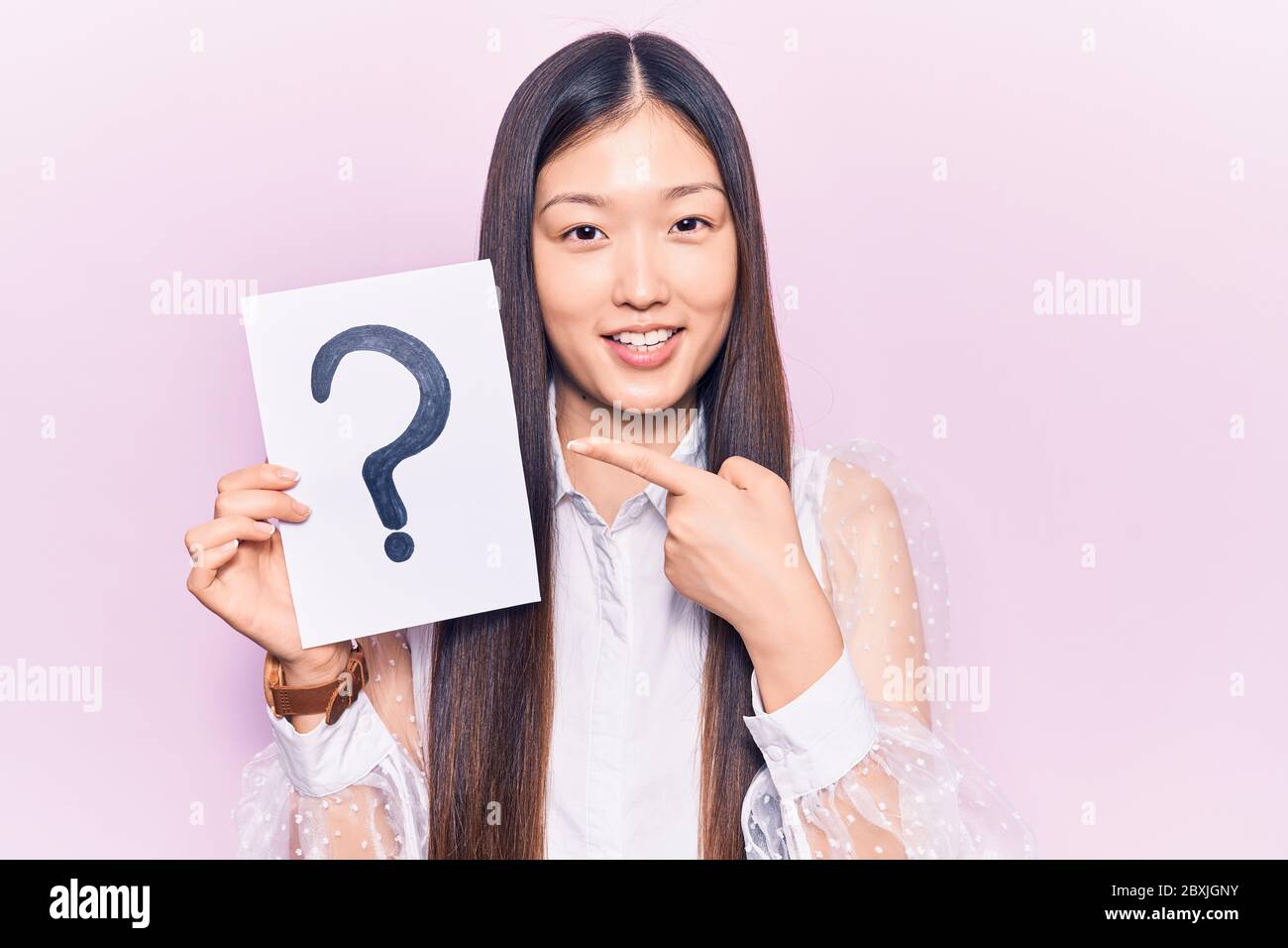 Young beautiful chinese woman holding question mark smiling happy ...
