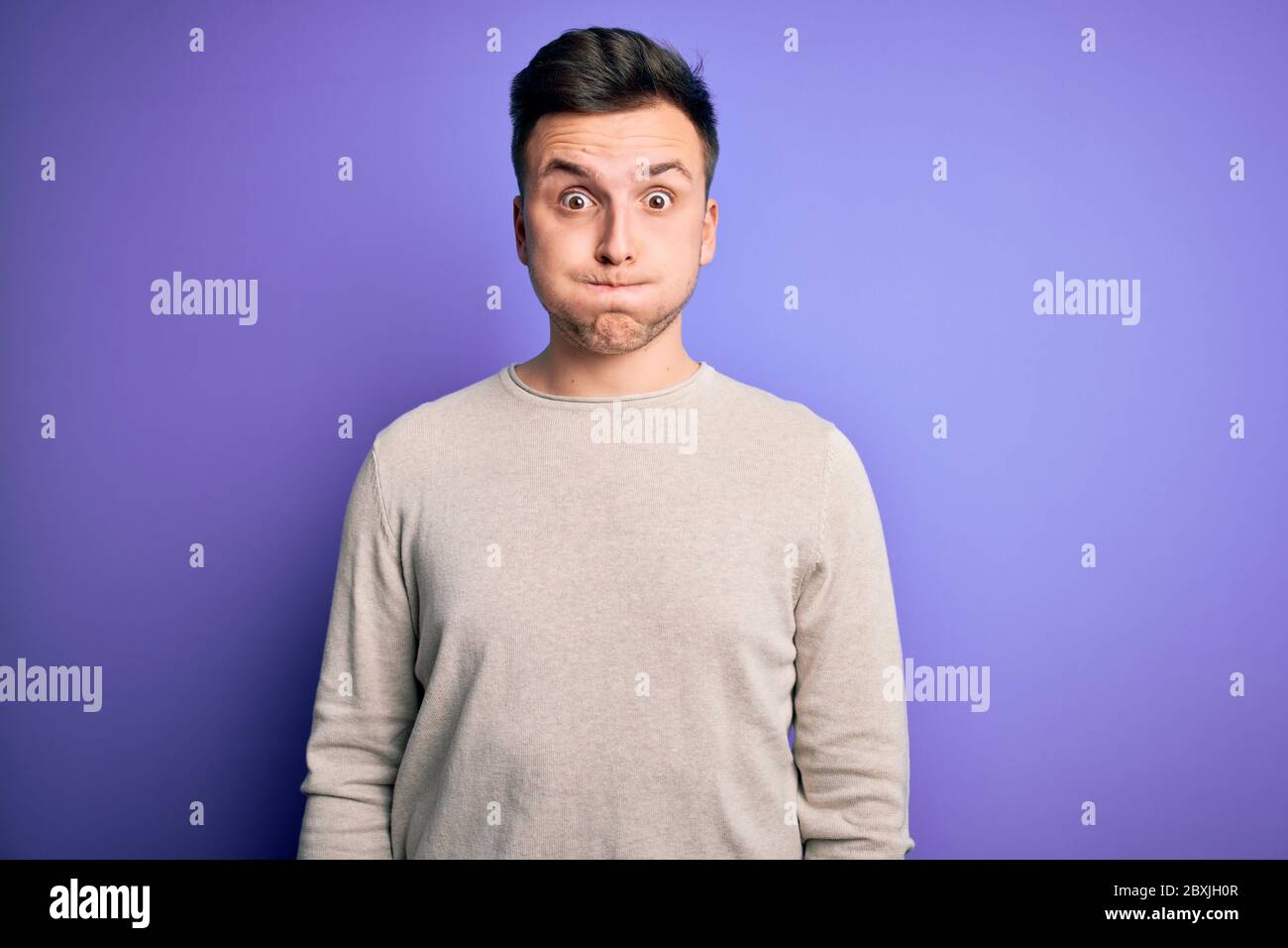 Young handsome caucasian man wearing casual sweater over purple ...