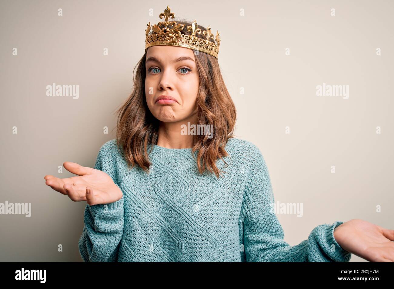 Young blonde girl wearing queen golden crown over isolated background ...