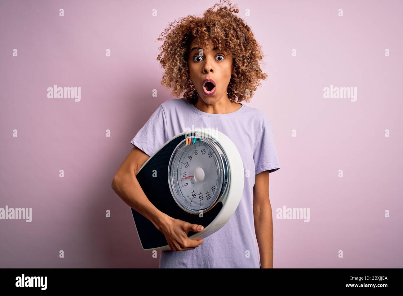 African american slim woman with curly hair holding scale over isolated ...