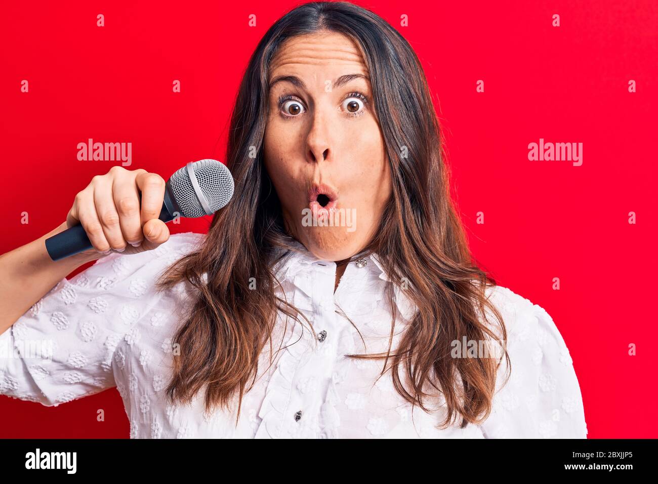 Young beautiful brunette singer woman singing song using microphone ...