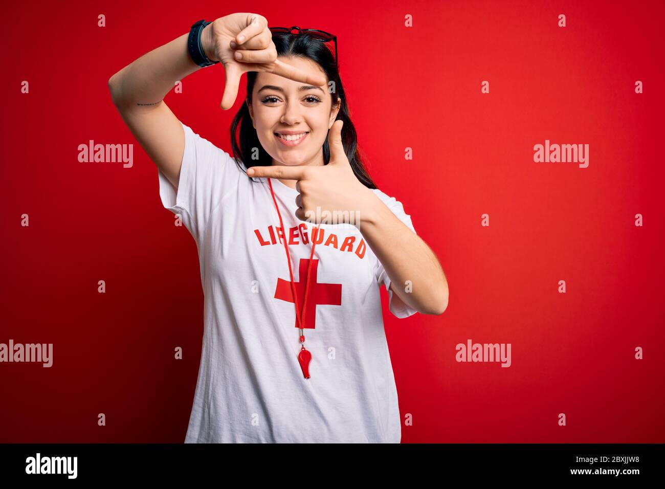 Young lifeguard woman wearing secury guard equipent over red background ...