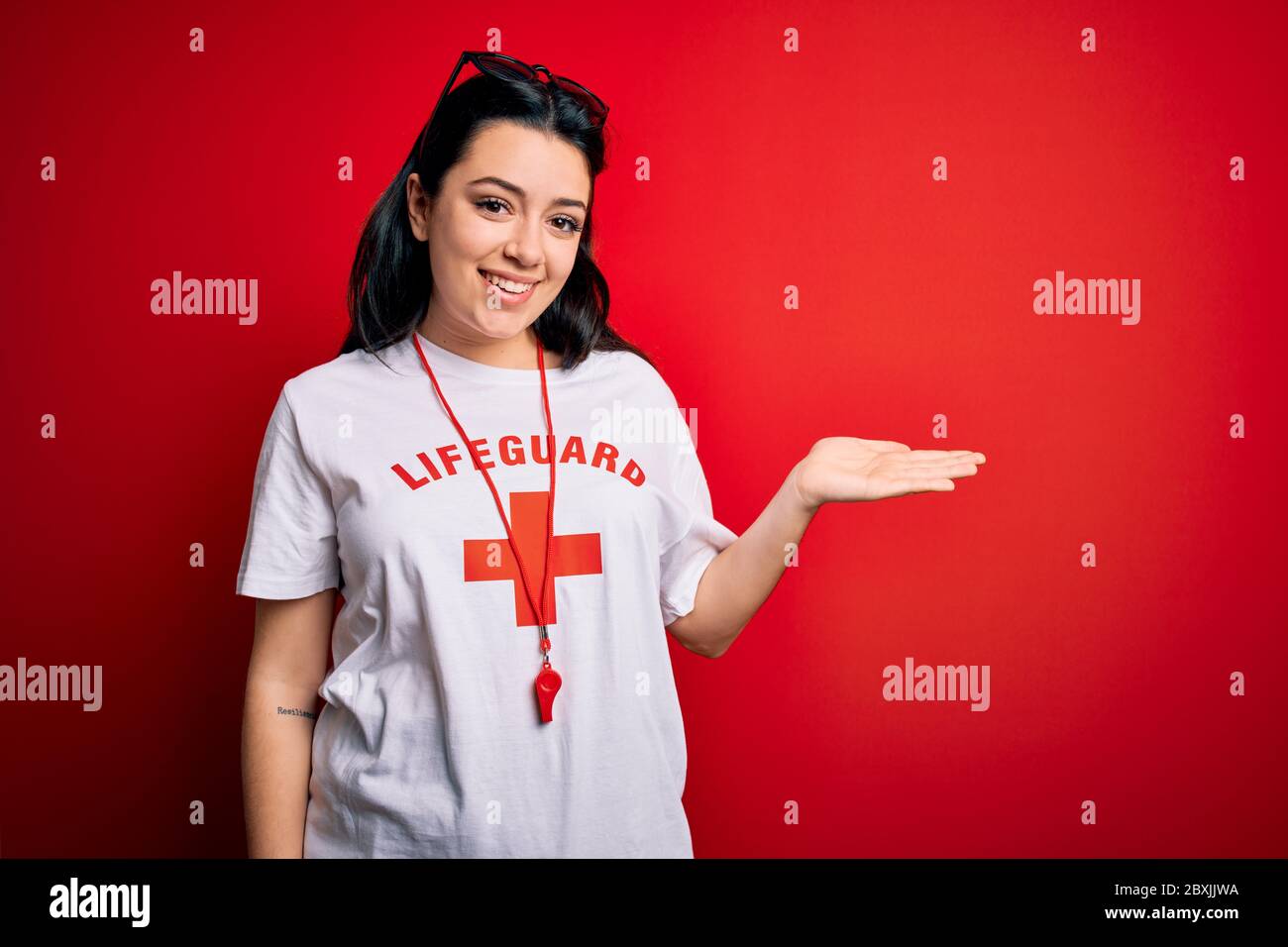 Young lifeguard woman wearing secury guard equipent over red background ...