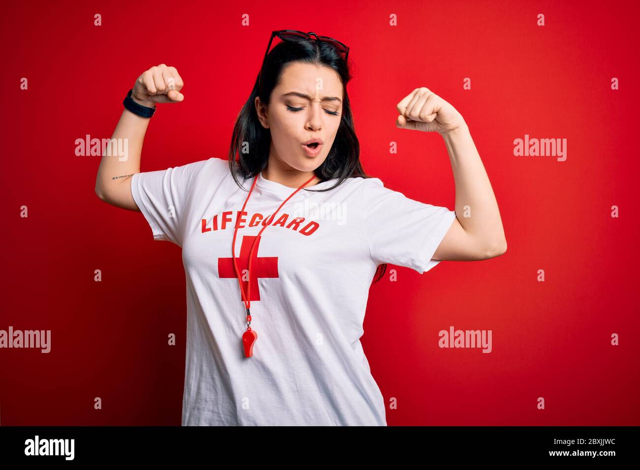 Young lifeguard woman wearing secury guard equipent over red background ...