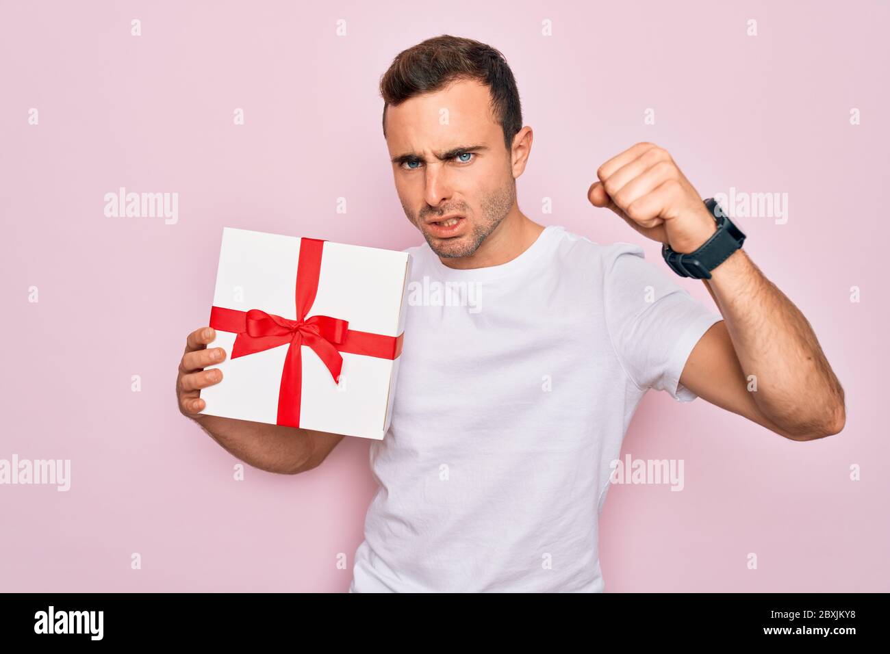 Young handsome man with blue eyes holding birthday present over ...