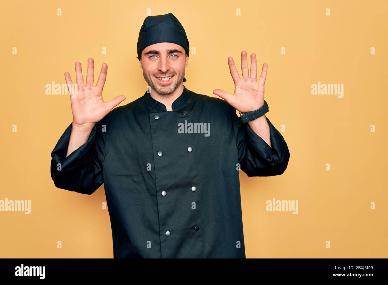 Young handsome cooker man with blue eyes wearing uniform and hat over ...
