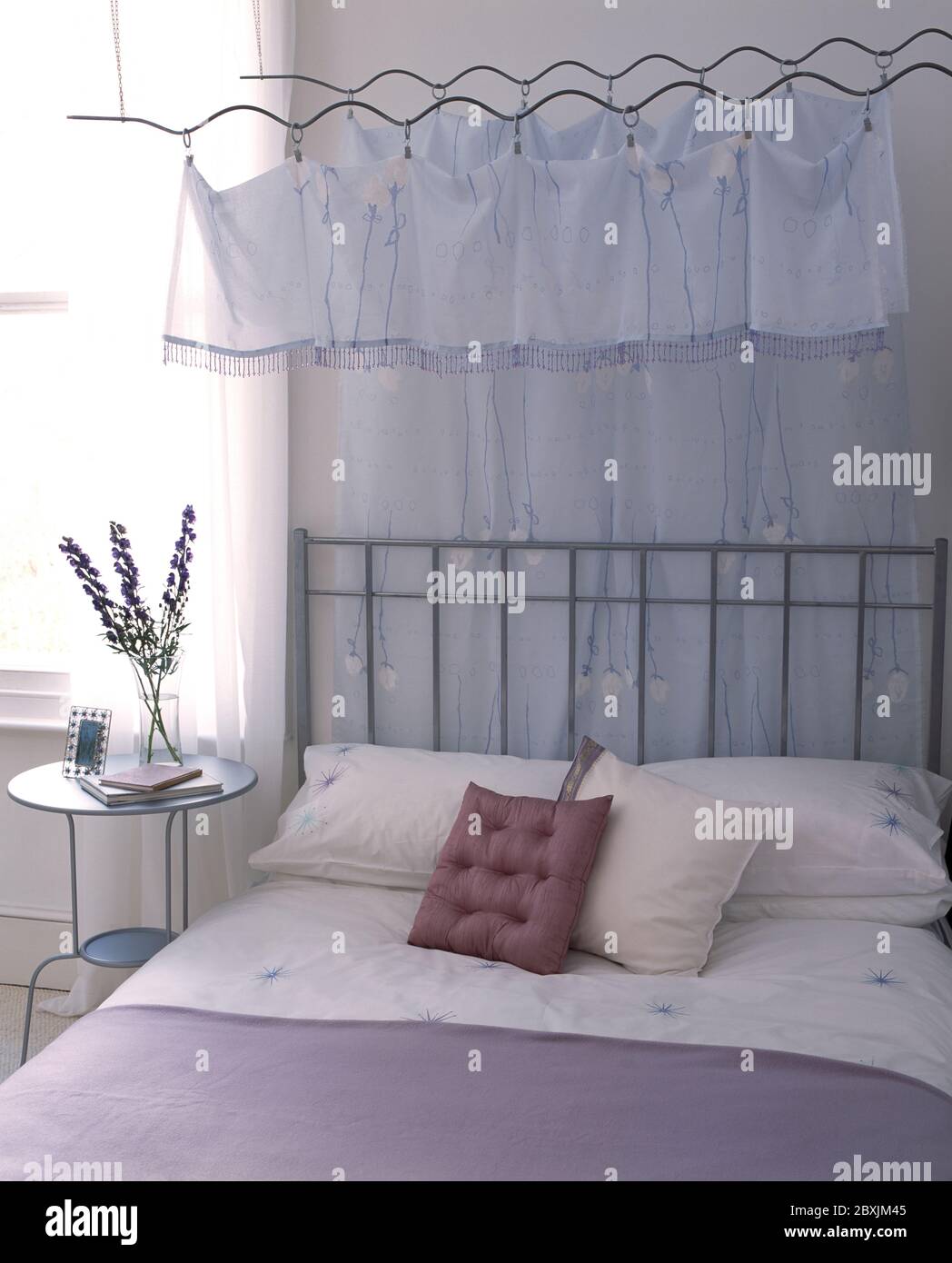 Decorateive curtain suspended behind bed Stock Photo - Alamy
