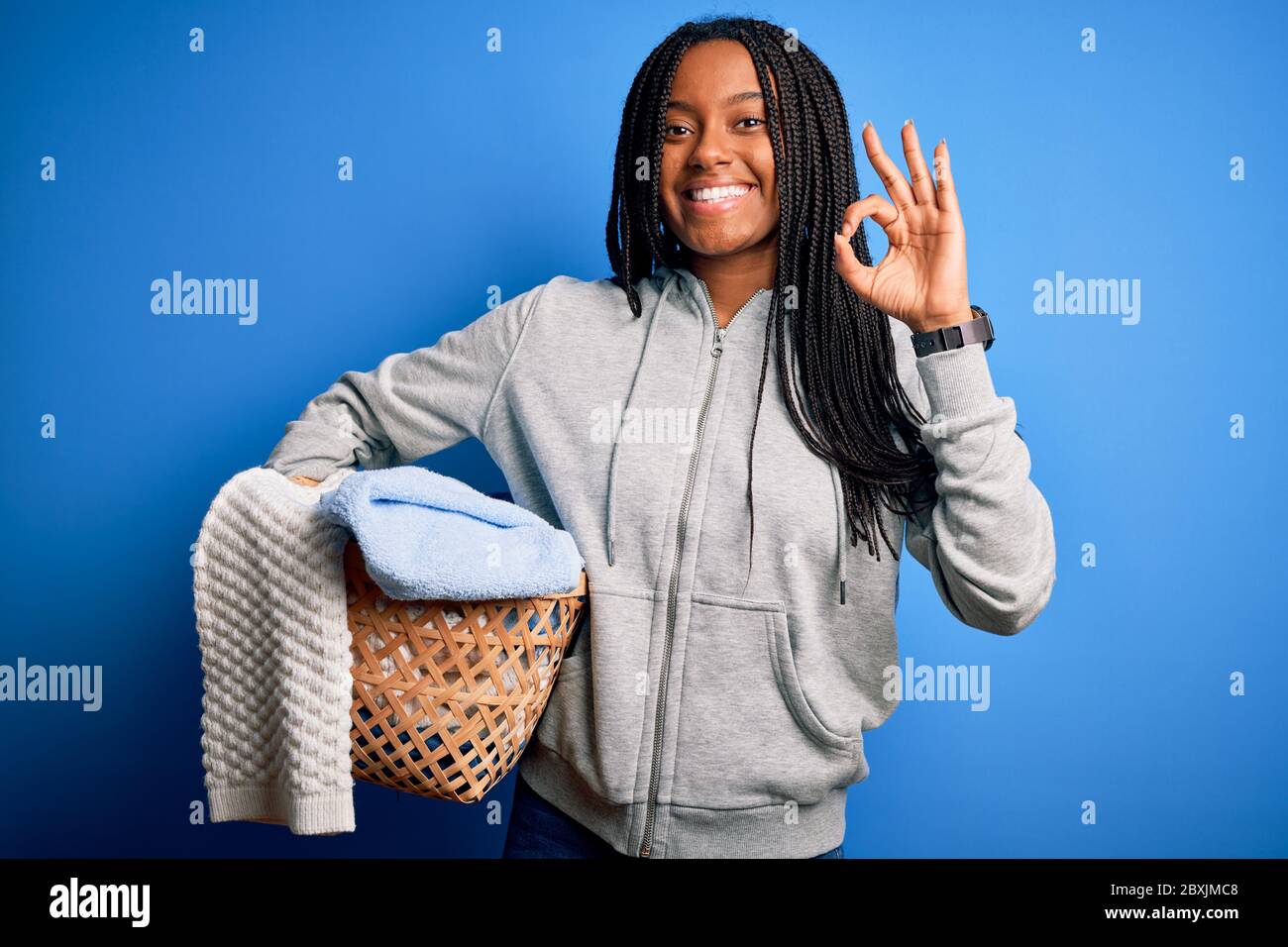 Young african american girl doing domestic housework holding laundry ...