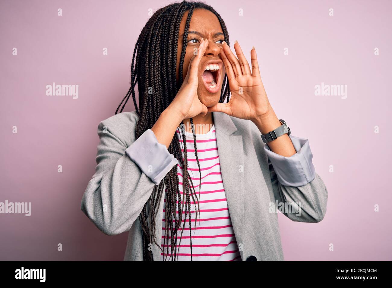 Young african american business woman standing over pink isolated background Shouting angry out ...