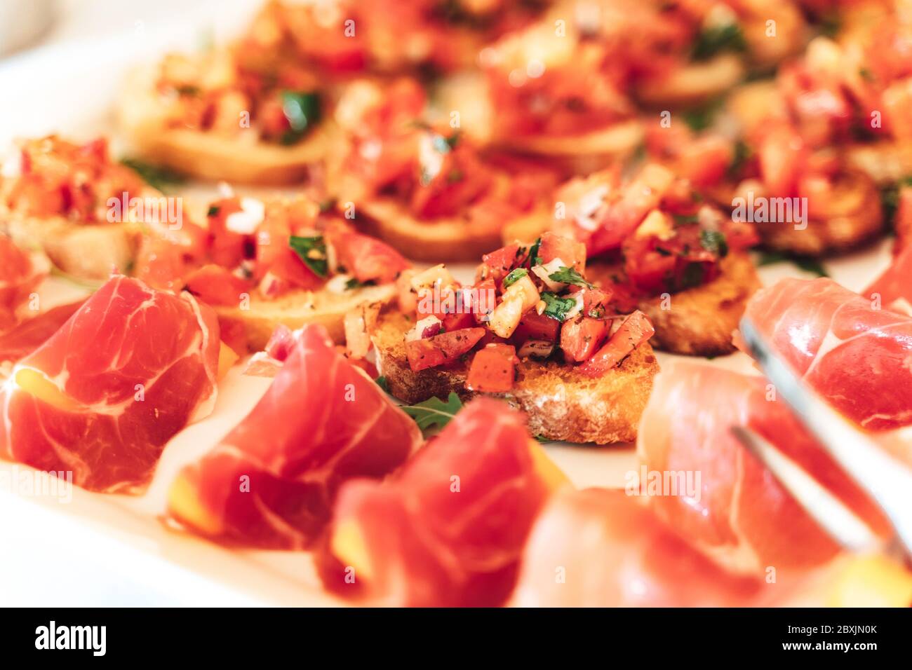 Tasty mini sandwich snacks and fruit rolled in ham on white tray on ...