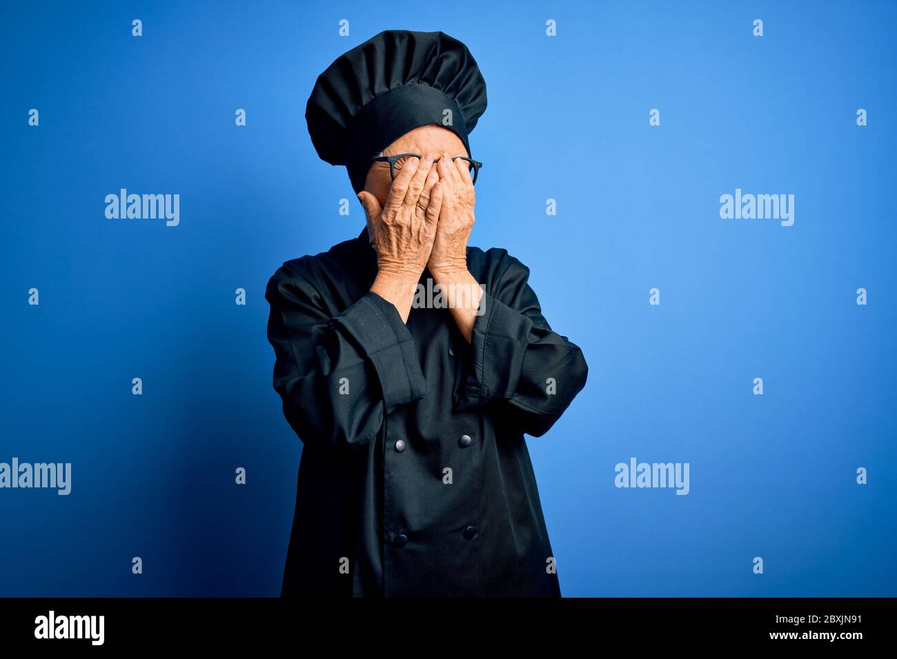 Senior beautiful grey-haired chef woman wearing cooker uniform and hat ...