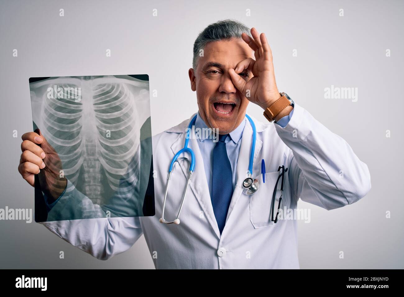Middle age handsome grey-haired doctor man holding chest xray over ...