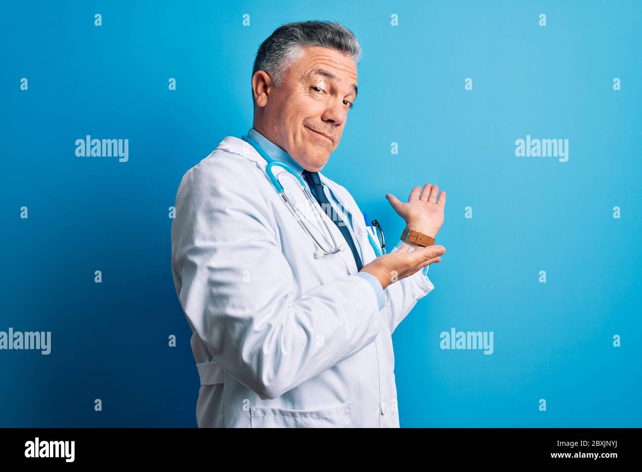 Middle age handsome grey-haired doctor man wearing coat and blue ...