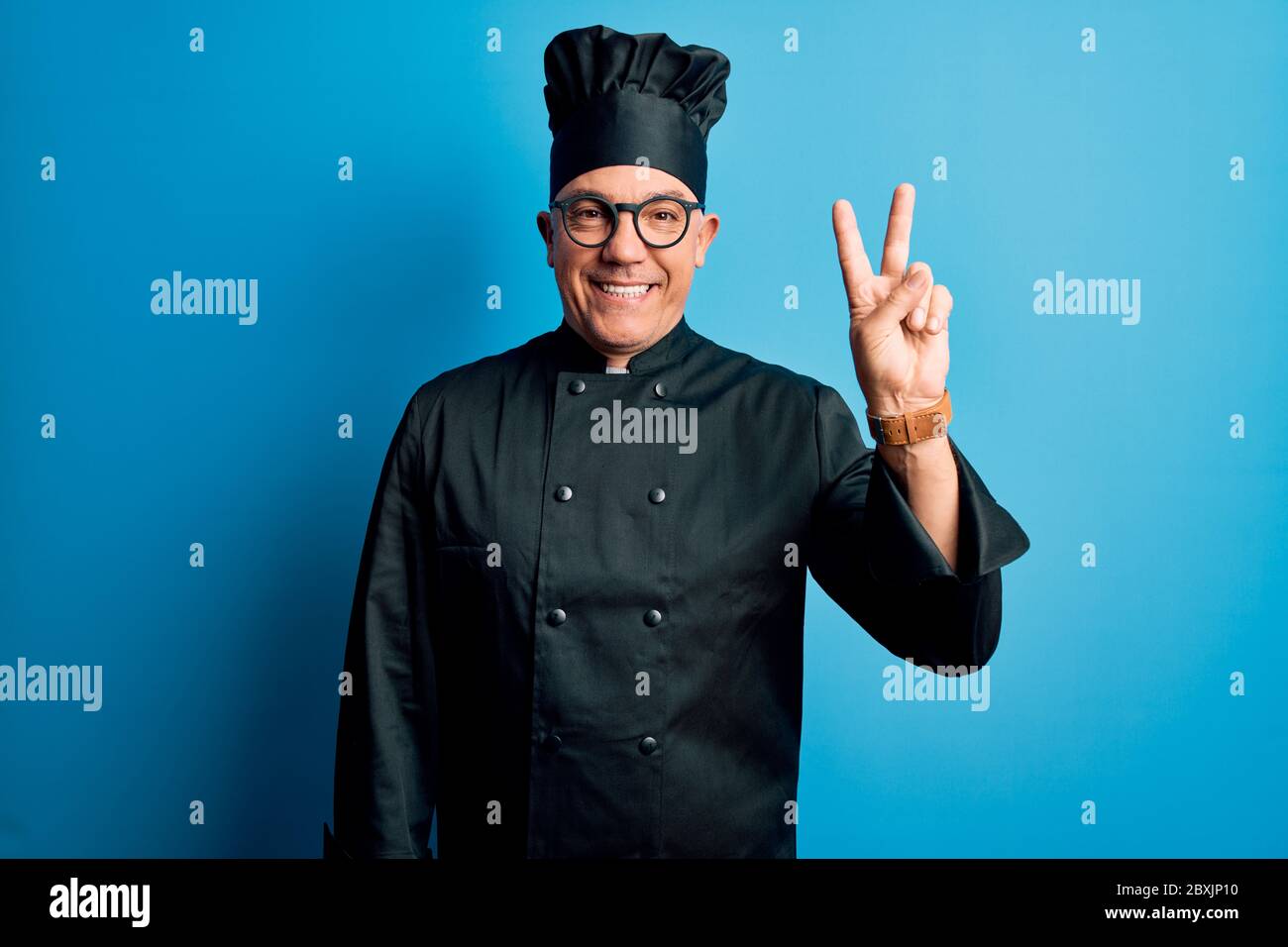 Middle age handsome grey-haired chef man wearing cooker uniform and hat ...