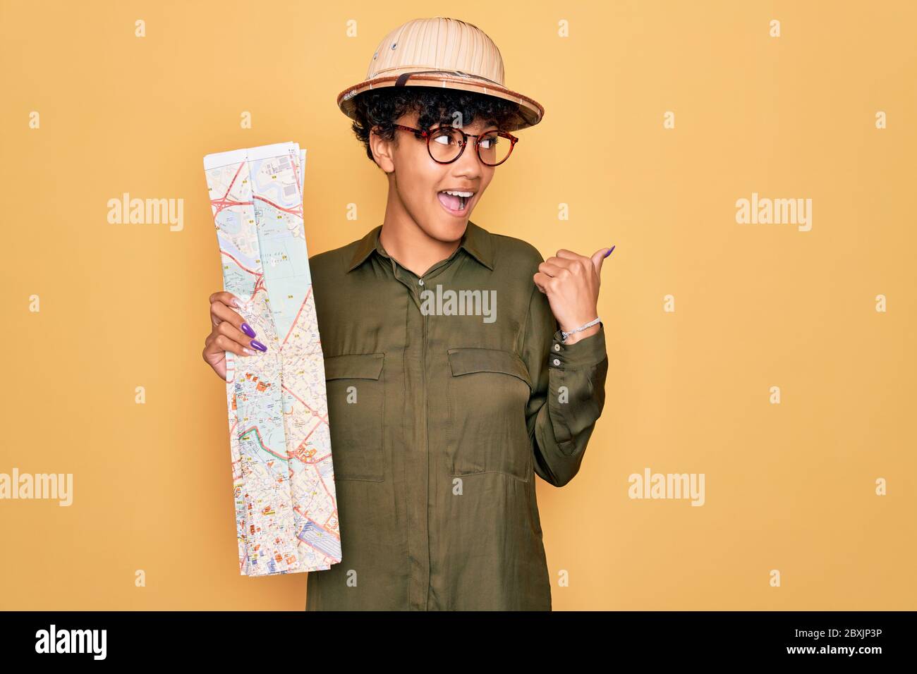 Beautiful african american explorer woman wearing hat holding city map ...