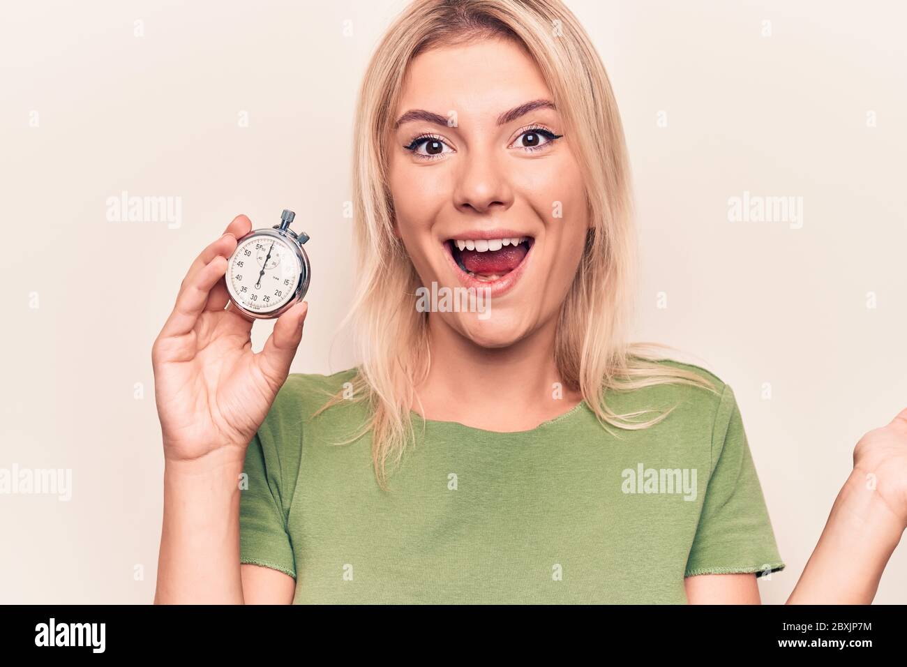 Young beautiful blonde woman doing countdown using stopwatch over white ...
