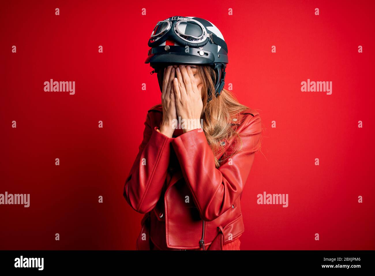 Young beautiful brunette motrocyclist woman wearing moto helmet over ...