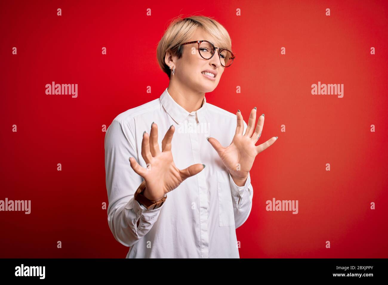 Young blonde business woman with short hair wearing glasses over red ...