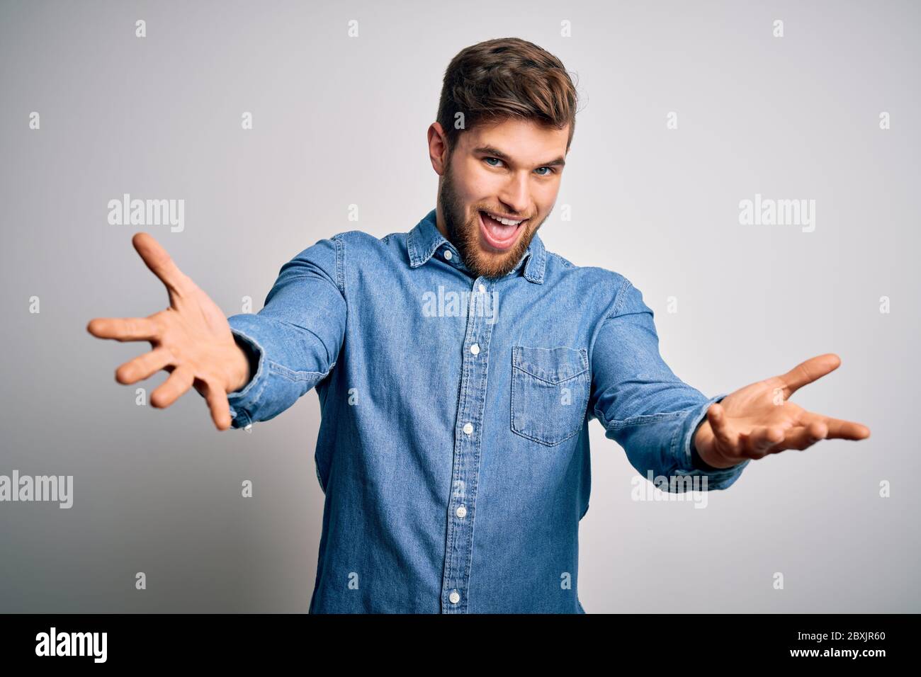 Young handsome blond man with beard and blue eyes wearing casual denim ...