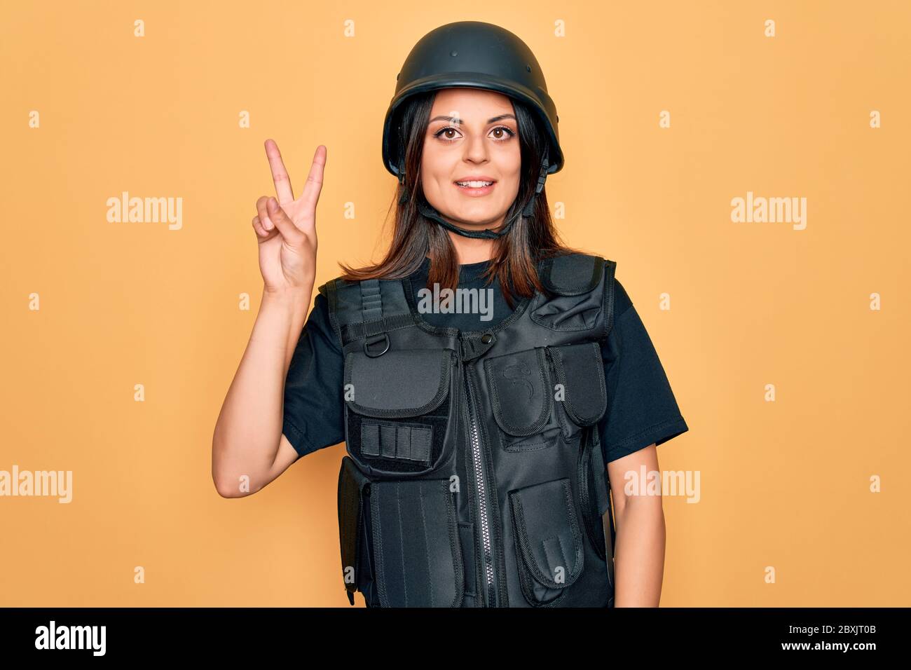 Young beautiful brunette soldier woman wearing bulletproof and security ...