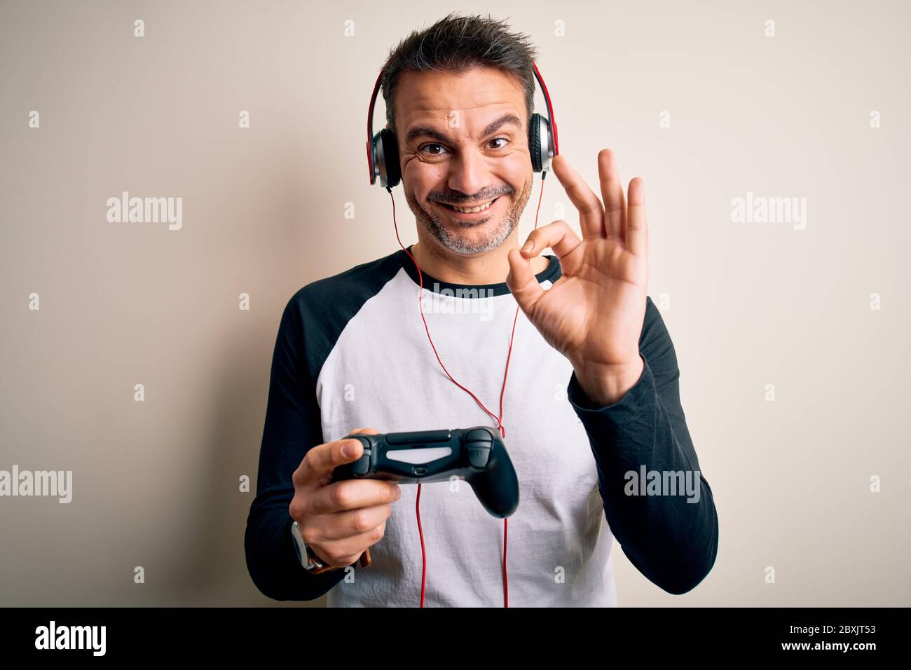 Young handsome gamer man playing video game using joystick and ...