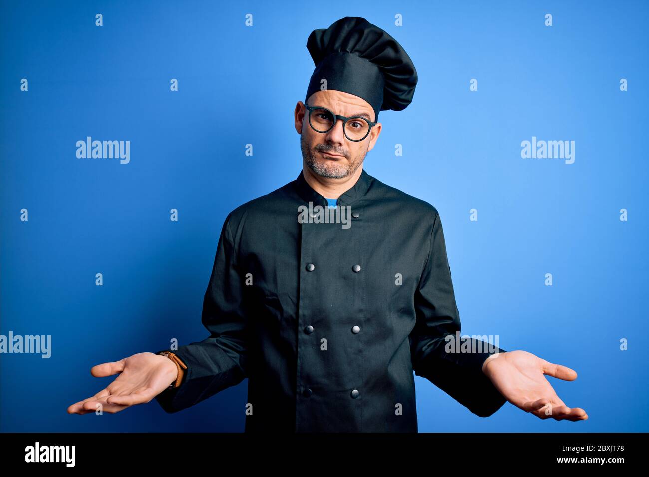 Young handsome chef man wearing cooker uniform and hat over isolated ...