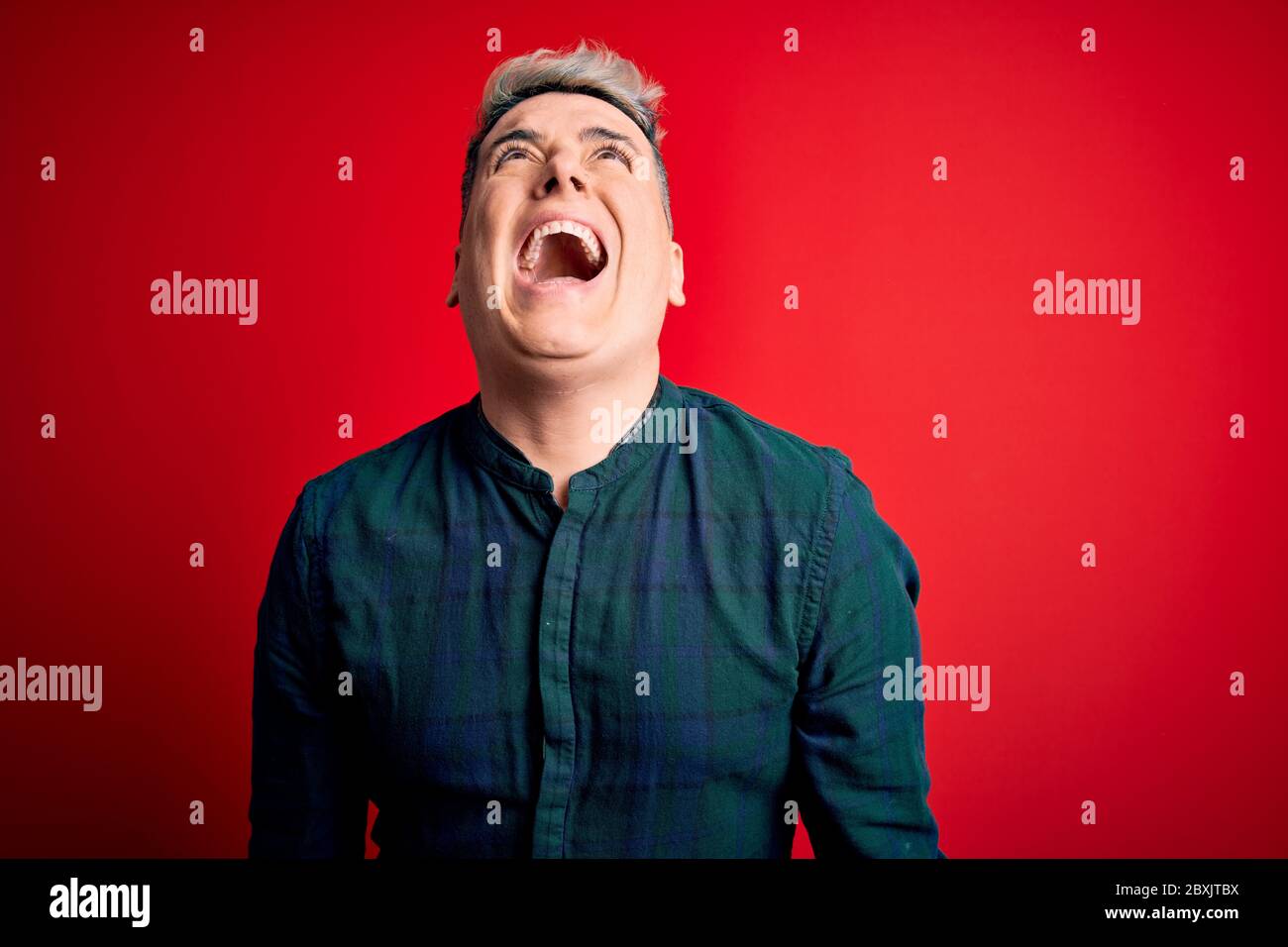 Young handsome modern man wearing elegant green shirt over red isolated ...