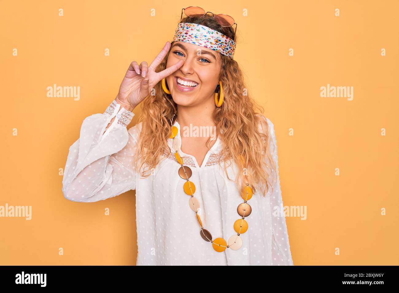 Young beautiful blonde hippie woman with blue eyes wearing sunglasses ...