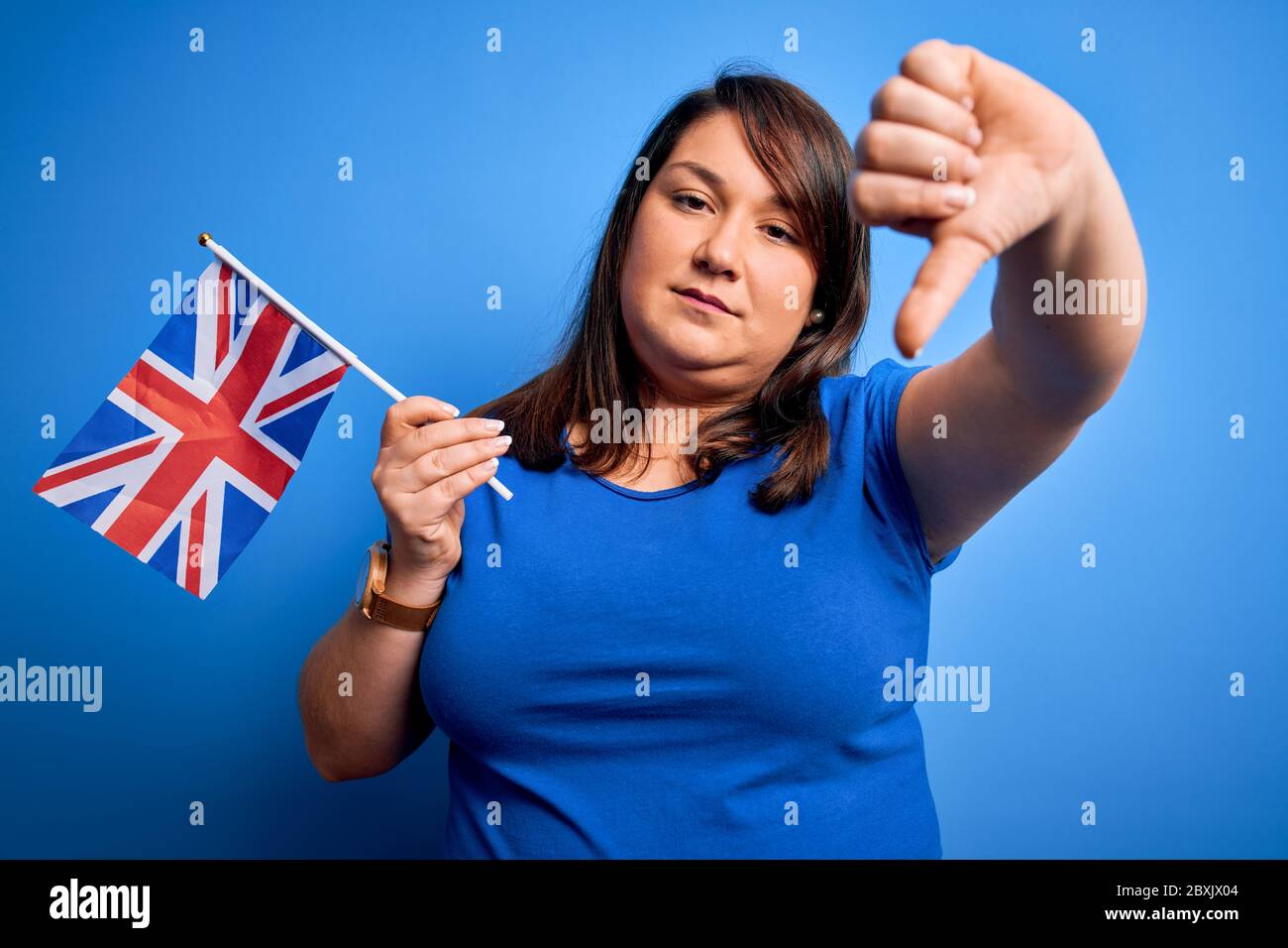 Beautiful plus size woman holding united kingdom flag over blue ...