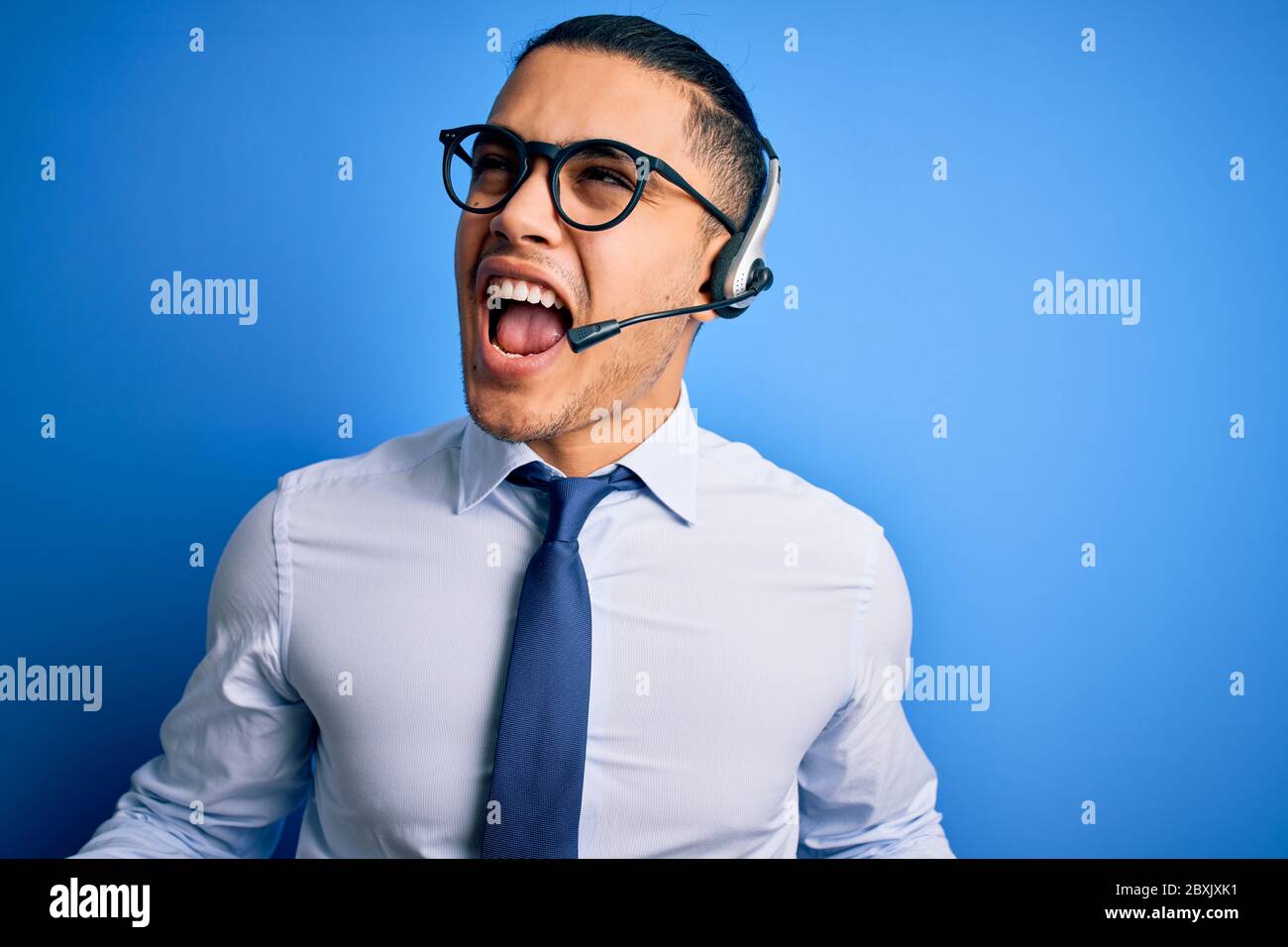 Young brazilian call center agent man wearing glasses and tie working ...