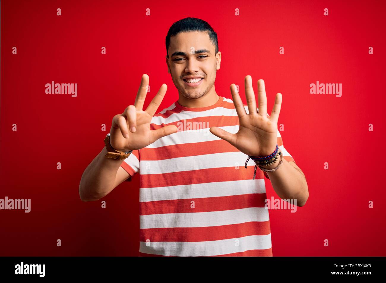 Young brazilian man wearing casual striped t-shirt standing over ...