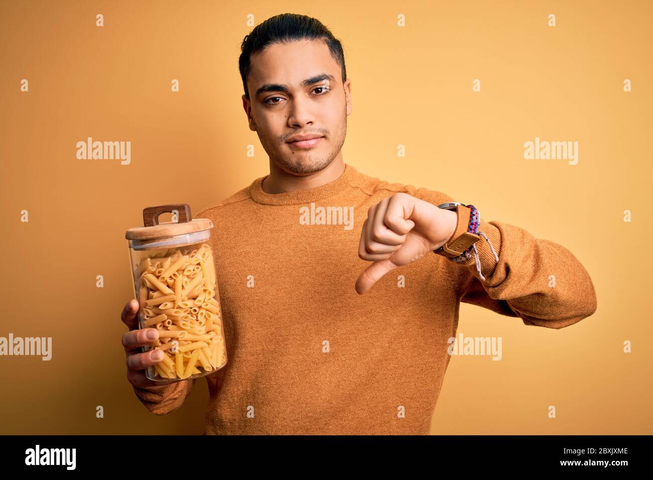 Young brazilian man holding jar with Italian dry pasta macaroni over ...