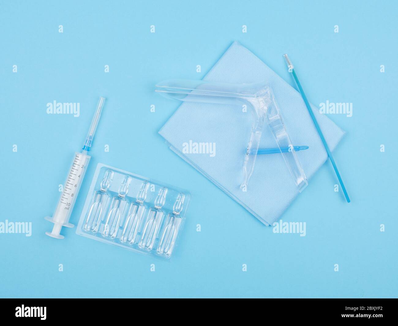 Gynecological examination kit, syringe and ampoule on blue background ...