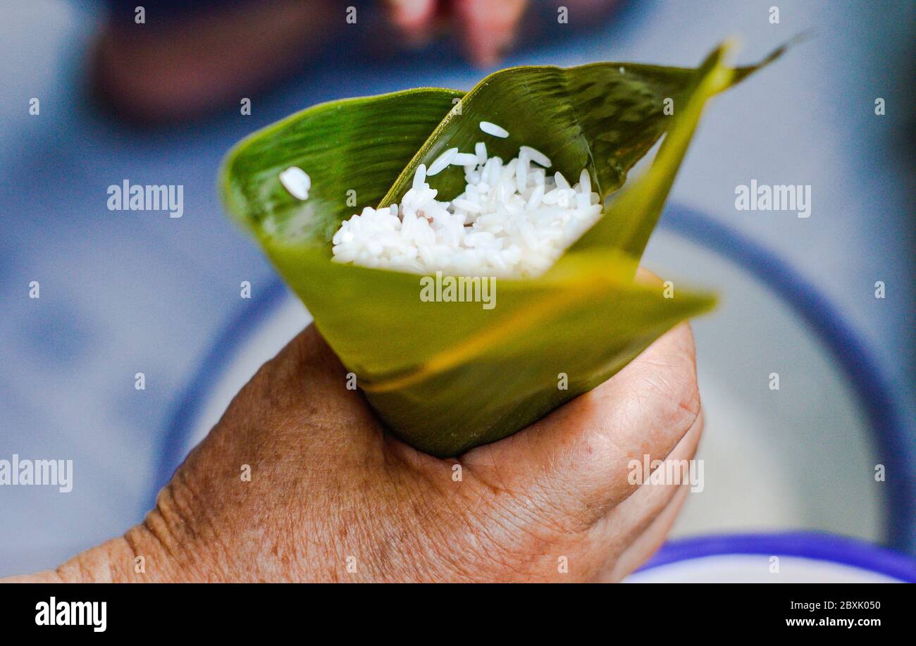 Hand holding leaf filled with sticky rice to make Zong zi, the ...