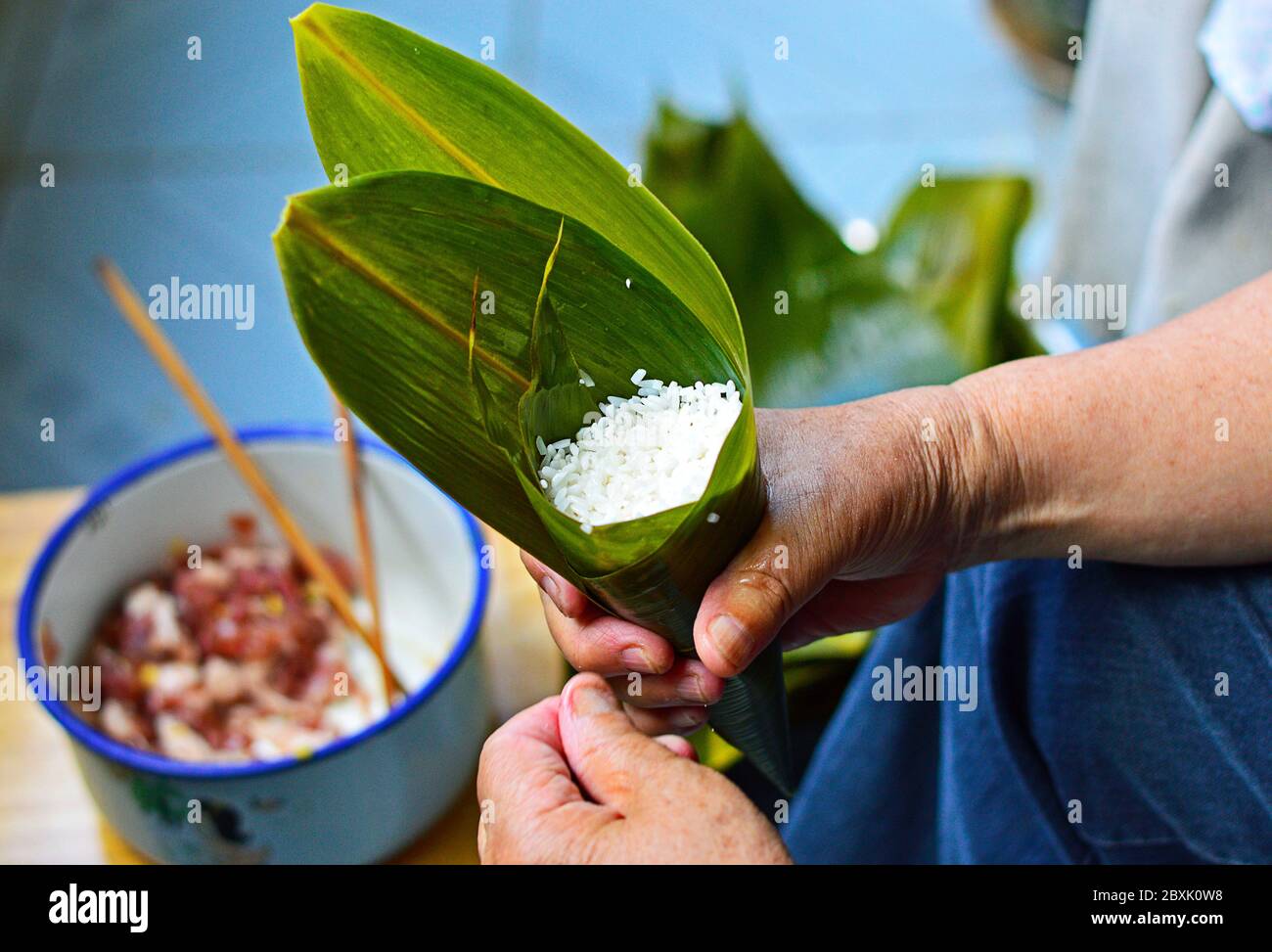 Hand holding leaf filled with sticky rice to make Zong zi, Chinese rice ...